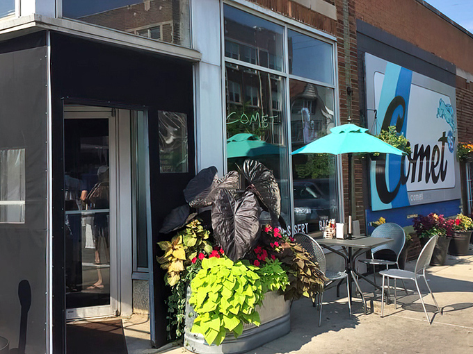 The inviting storefront of Comet Cafe beckons with its bright blue signage and lush planters. Milwaukee's East Side gem awaits your discovery.