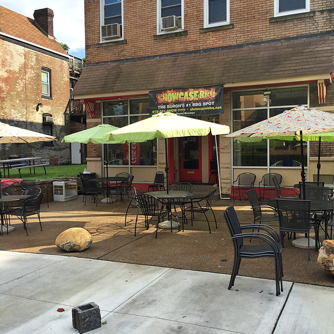 The unassuming brick exterior of Showcase BBQ proves once again that the best food often hides behind the most modest facades. Those colorful umbrellas promise a warm welcome regardless of the weather.