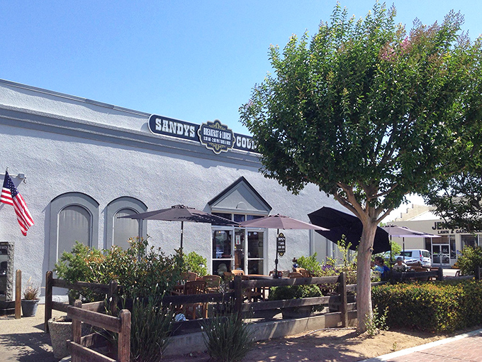 The white-washed exterior of Sandy's Country Junction welcomes hungry travelers with rustic charm and a shaded patio that practically whispers, "Come sit a spell."