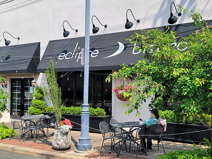 The outdoor seating area beckons like an urban oasis, where hanging flower baskets and lush greenery transform a simple sidewalk into a dining sanctuary.