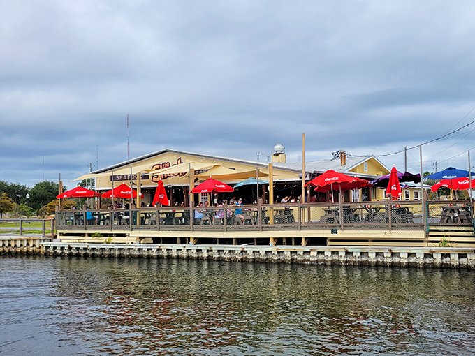 The quintessential Florida waterfront dining experience awaits at The Shack, where those red umbrellas promise both shade and seafood salvation.