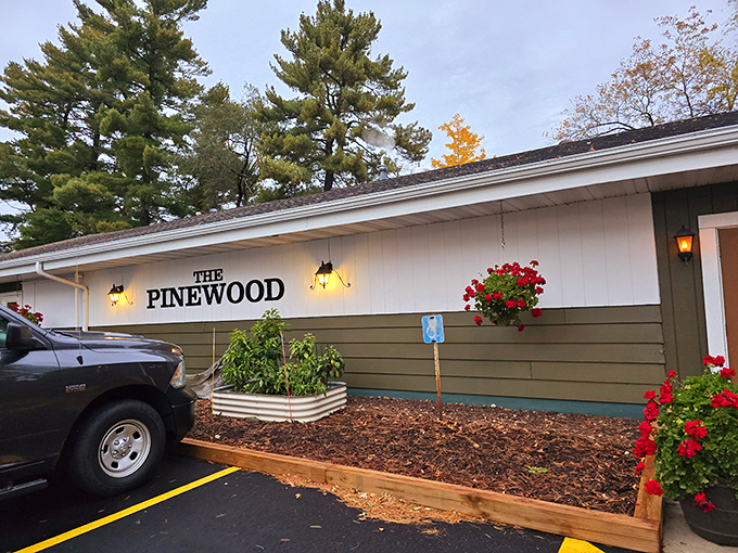The welcoming entrance to Pinewood Supper Club, where hanging flower baskets and warm lighting promise the authentic Wisconsin supper club experience awaits inside.
