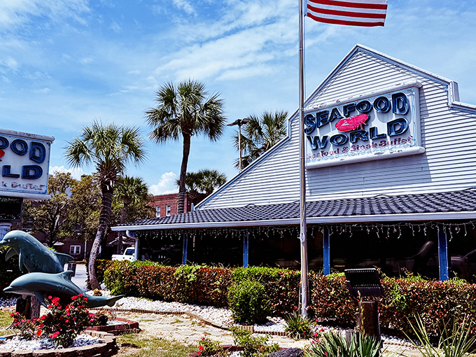 The iconic white-sided building with its bold blue signage stands like a beacon for seafood lovers, palm trees swaying in welcome.