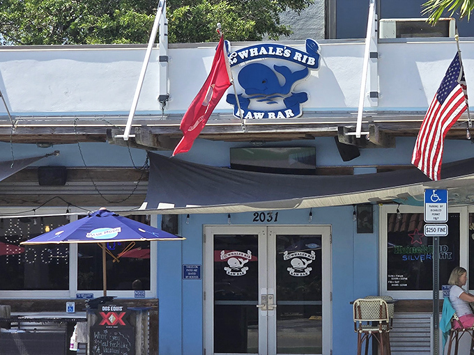 The blue facade of The Whale's Rib stands as a beacon of seafood salvation, where flags flutter in the ocean breeze and hungry patrons find their way home.