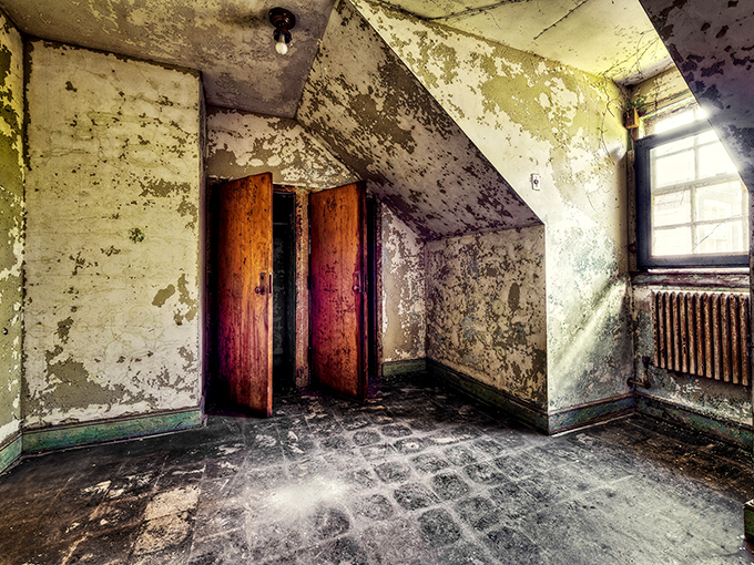 Time stands still in this eerie patient room, where peeling walls and weathered wooden doors whisper stories of a bygone institutional era.