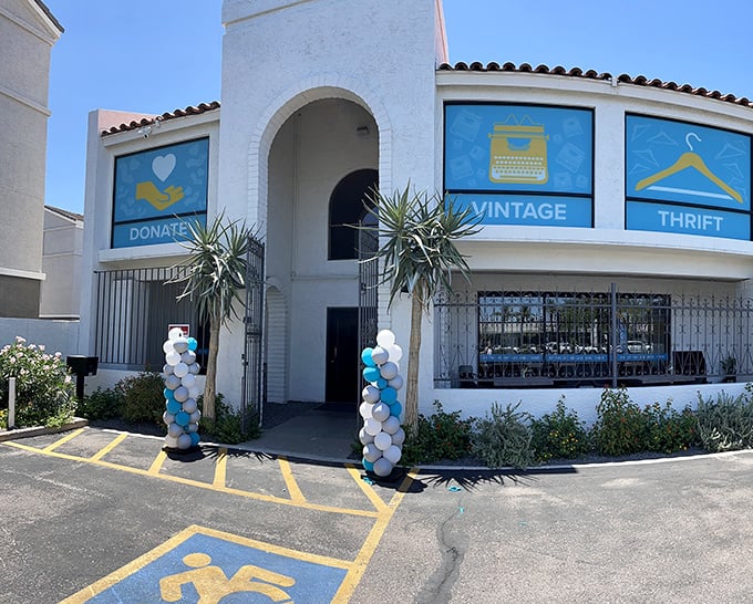 The welcoming facade of Thrift to Thrive beckons with its cheerful blue signage and white stucco charm. Bargain paradise awaits!