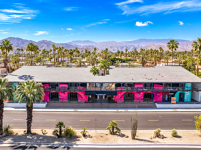 The pink palace of bargains stands proudly against the desert mountains, like a flamingo promising treasures within its walls.