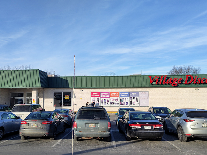 The iconic red cursive sign of Village Discount Outlet stands against an Ohio blue sky, promising treasure hunters a paradise of possibilities within.