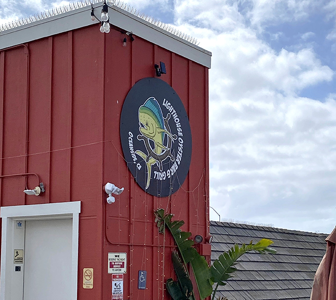 The bright red exterior of Lighthouse Oyster Bar & Grill stands out like a culinary lighthouse, complete with a fish logo that seems to say "follow me to flavor!"