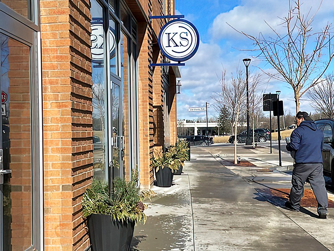 Kitchen Social's understated brick exterior with its circular "KS" sign promises culinary adventures that far exceed its modest storefront appearance.