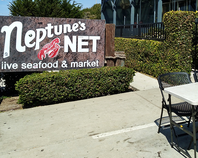 That weathered sign promises adventure &ndash; Neptune's Net delivers oceanic treasures without the pretense of fancier establishments.