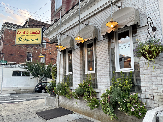 The classic white-painted brick exterior of Dante & Luigi's, with its charming awnings and hanging flower baskets, promises old-world Italian hospitality before you even step inside.