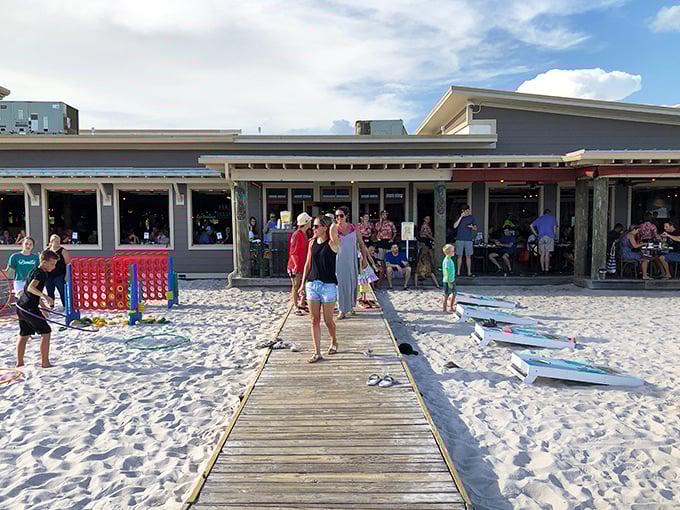 The wooden boardwalk beckons like a runway to flavor paradise, guiding hungry beachgoers from sand to sustenance while a giant Connect Four game promises entertainment between bites.