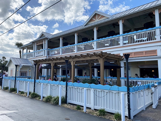 Blue wave accents adorn the white picket fence surrounding the outdoor dining area, where Florida's famous sunshine creates the perfect backdrop for seafood indulgence.