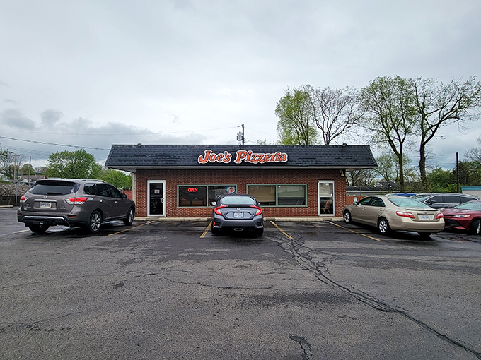 The modest brick exterior of Joe's Pizzeria stands like a beacon of hope for the pizza-deprived, its orange sign promising delicious salvation within.