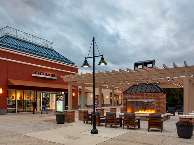 As dusk settles, the Coach storefront glows invitingly next to the pergola-covered seating area—a shopper's oasis complete with dancing flames and twinkling lights.