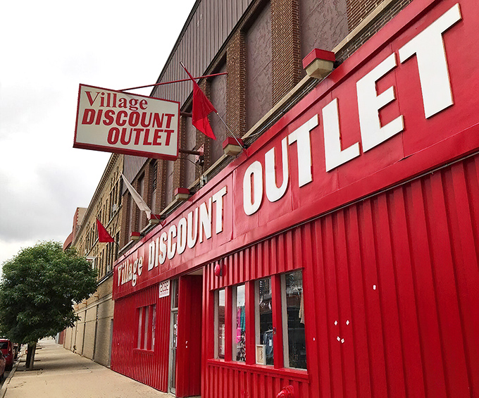 The unmistakable crimson facade of Village Discount stands like a beacon of bargain hope on Milwaukee Avenue, promising treasures within those bright red walls.