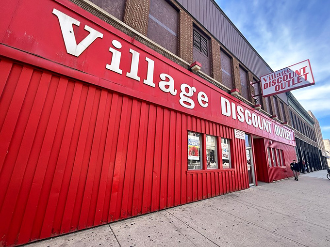 The unmistakable crimson facade of Village Discount stands like a beacon of bargain hope on Milwaukee Avenue, promising treasures within its no-frills exterior.