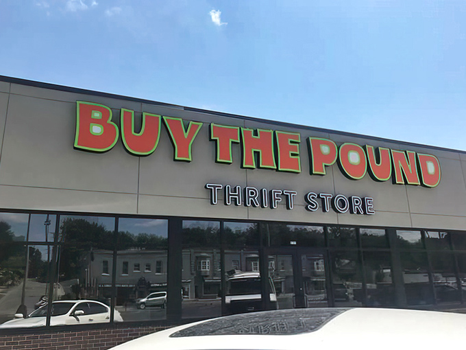 The vibrant orange and green sign of Buy The Pound beckons bargain hunters like a retail oasis in Kansas City's urban landscape.