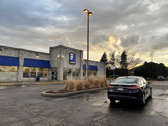 The Janesville Goodwill welcomes treasure hunters with its distinctive blue awnings and stone facade, standing like a castle of second-hand wonders at sunset.
