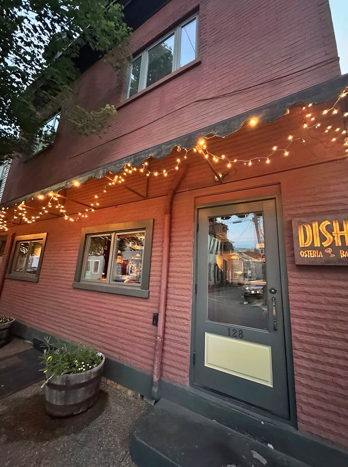 The pink brick exterior of Dish Osteria Bar glows at twilight, string lights adding a touch of magic to this Pittsburgh gem.