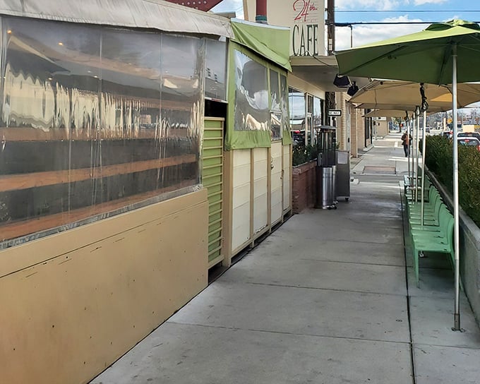 The unassuming exterior of 24th Street Cafe, where green umbrellas promise shade and the promise of comfort food beckons from within.