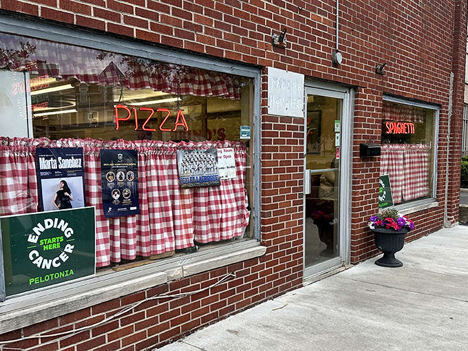 The red-checkered curtains and neon signs are like a time machine to simpler days when pizza joints didn't need fancy facades to prove their worth.