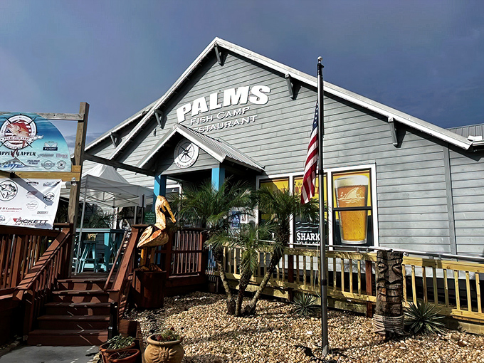 The pale blue exterior of Palms Fish Camp Restaurant beckons like an old friend, complete with wooden deck and American flag fluttering in the coastal breeze.