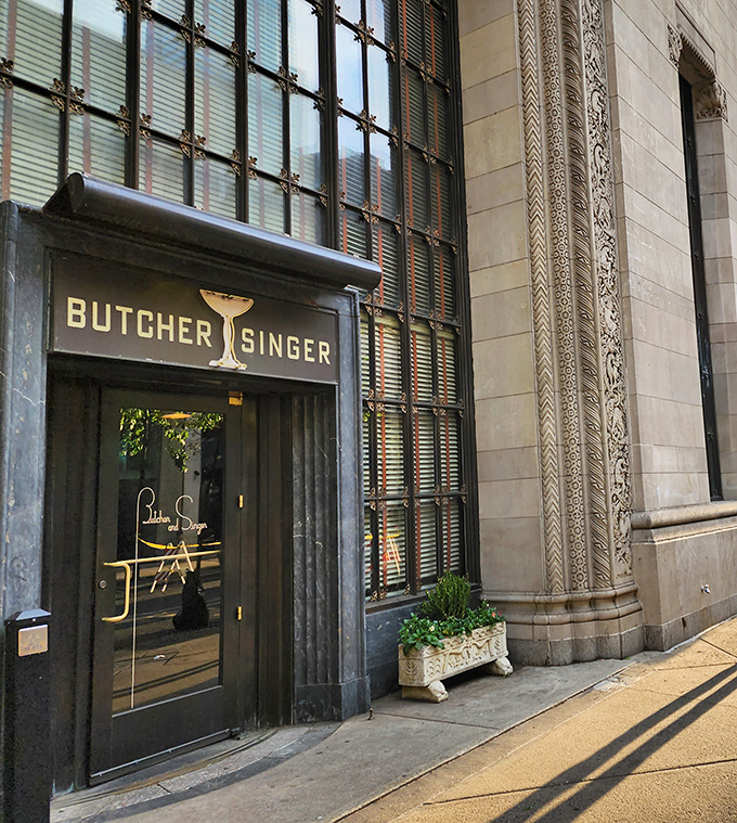 The entrance to Butcher and Singer stands like a portal to another era, where the martini glass logo promises sophisticated pleasures within.