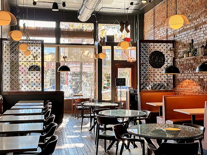 Sunlight streams through the windows of 929 Kitchen & Bar's dining room, where orange pendant lights and exposed brick create a modern yet cozy atmosphere.