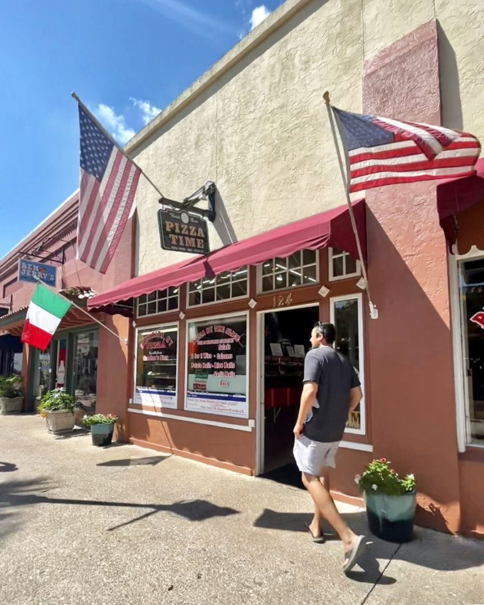 The unassuming exterior of Pizza Time belies the culinary treasures waiting inside. Red awnings and patriotic flair welcome hungry visitors.