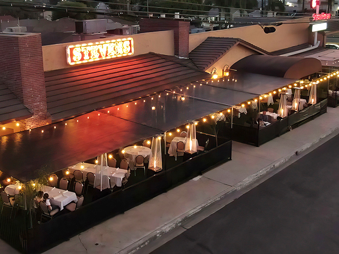 The iconic neon STEVENS sign glows like a beacon for meat lovers, while heat lamps stand guard over white-clothed tables. Dinner with a view!