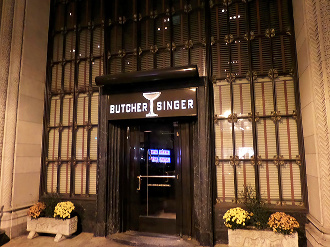 The unassuming entrance to Butcher and Singer beckons like a secret passage to the Rat Pack era, promising culinary time travel behind those elegant doors.