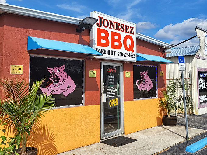 The vibrant orange and burgundy exterior of Jonesez BBQ stands out like a beacon for hungry travelers, complete with those cheeky pink pig mascots.
