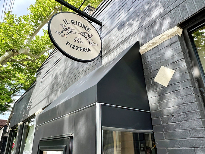 The sleek black exterior of Il Rione might be understated, but that circular sign promises pizza magic within Cleveland's Ohio City neighborhood.