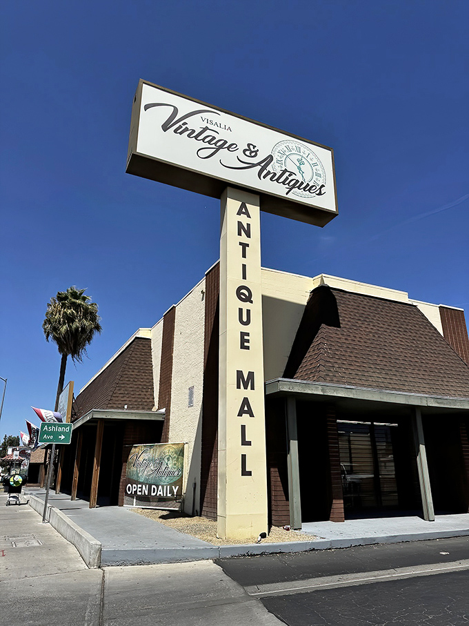 The distinctive brown-and-cream exterior of Visalia Vintage & Antiques stands like a time portal on Main Street, palm trees swaying as if beckoning treasure hunters inside.