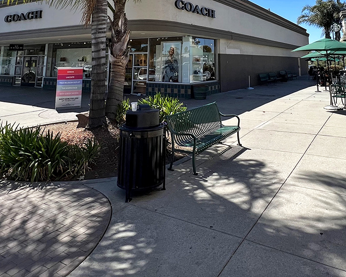 The iconic entrance to Gilroy Premium Outlets, where palm trees stand guard over fashion treasures like sentinels of style with discounted price tags.