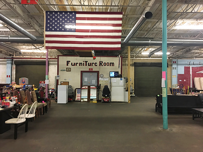 The furniture section at Joey's Thrift Mall stands proudly under Old Glory, where patriotism meets bargain hunting in a treasure hunter's paradise.