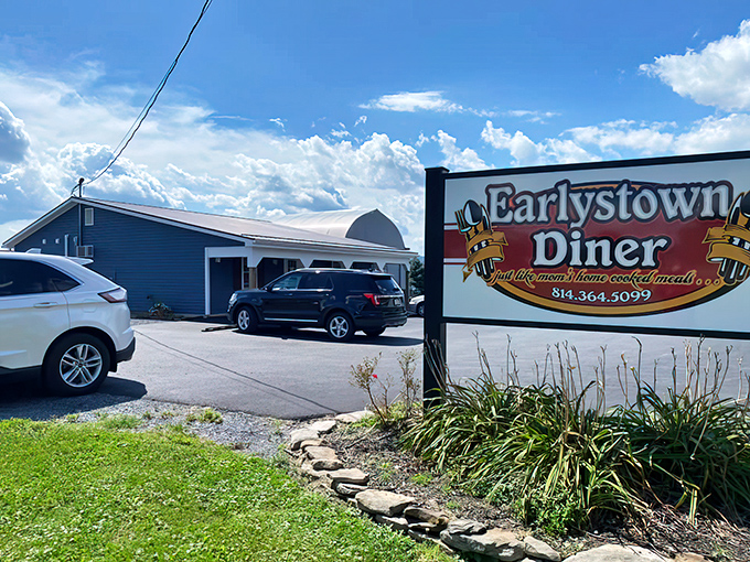 The humble facade of Earlystown Diner rises like a beacon for hungry travelers, with blue skies above hinting at comfort food and warm welcomes inside.