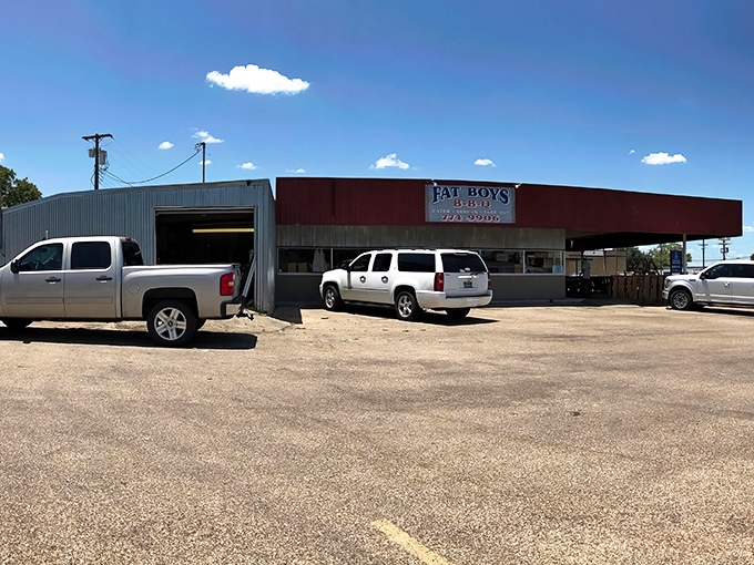 A wider view reveals Fat Boy's modest kingdom where pickup trucks gather like pilgrims at a smoky shrine to Texas BBQ tradition.