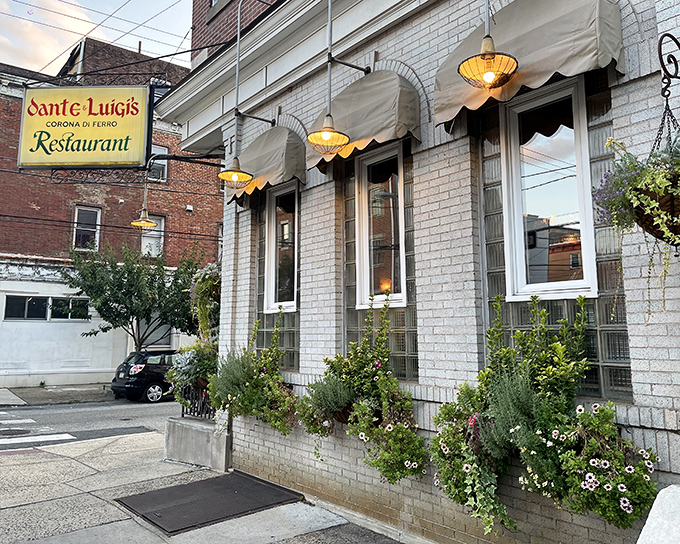 The charming white brick exterior of Dante & Luigi's beckons like an old friend, complete with classic awnings and flower baskets that whisper, "Come in, you're family now."