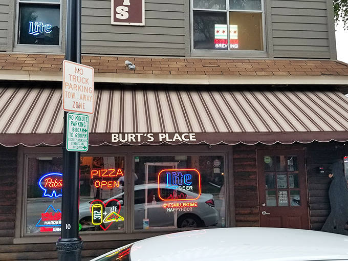 The unassuming gray exterior of Burt's Place, with its vintage neon sign, proves that pizza paradise often hides in plain sight.