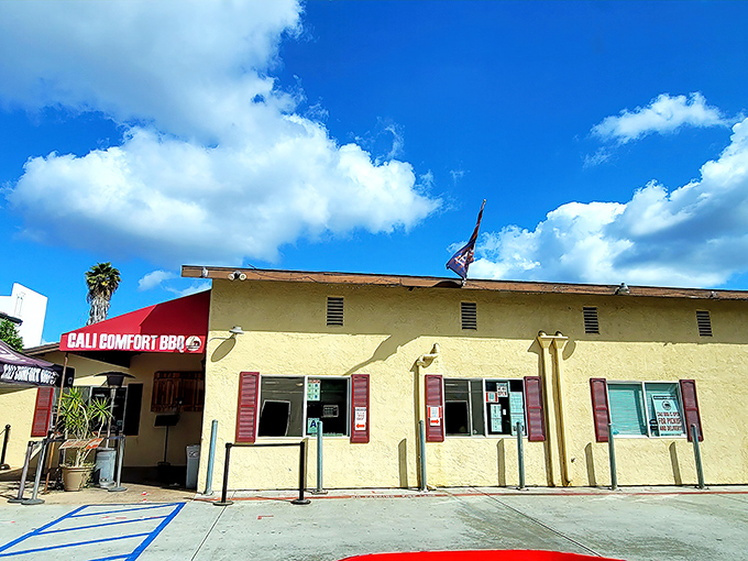 The humble stucco exterior of Cali BBQ might not scream "destination," but those flags flying proudly say "serious barbecue happens here."