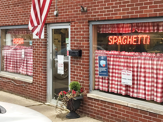 The classic red-checkered curtains and neon signs are like a time machine to simpler days when pizza joints didn't need fancy facades to prove their worth.