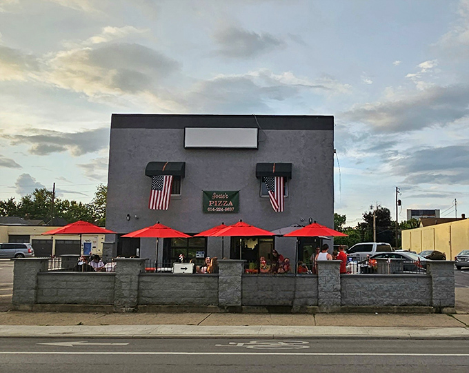 The gray fortress of flavor stands proudly on West Broad Street, its red umbrellas beckoning like culinary lighthouses to pizza pilgrims.