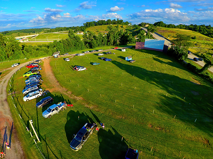 Aerial view of nostalgia: Cars dotting the grassy field like colorful beetles, all facing that magnificent white screen&mdash;cinema as nature intended.