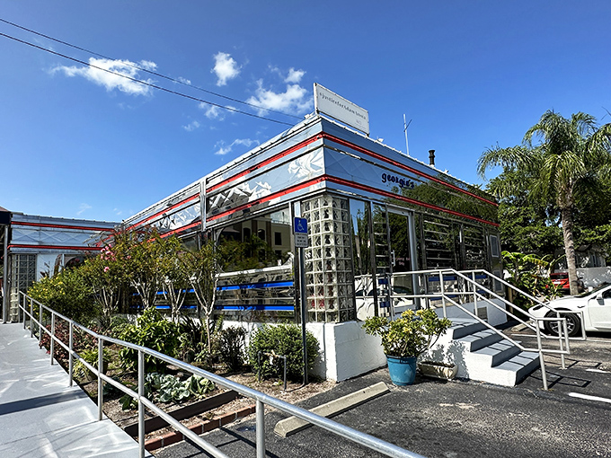 The gleaming stainless steel exterior of Georgie's Diner catches Florida sunshine like a time machine from the 1950s, complete with classic red trim and glass block windows.