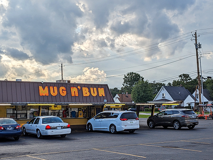 The iconic Mug-n-Bun sign glows against an Indiana sky, beckoning hungry travelers like a neon lighthouse for comfort food enthusiasts.