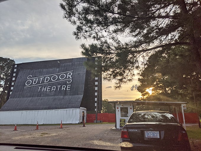 The iconic screen of Raleigh Road Outdoor Theatre stands tall against the twilight sky, a celluloid sentinel guarding memories of movie nights past.