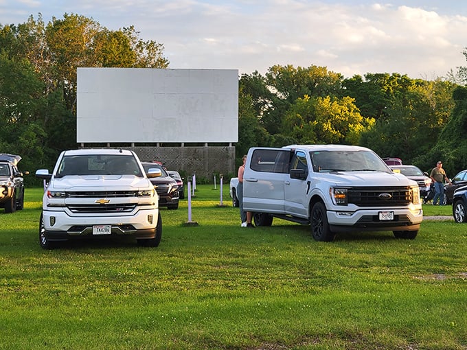 Trucks and SUVs line up facing the blank canvas of possibility. Soon, movie magic will transform this field into a communal living room under the stars.